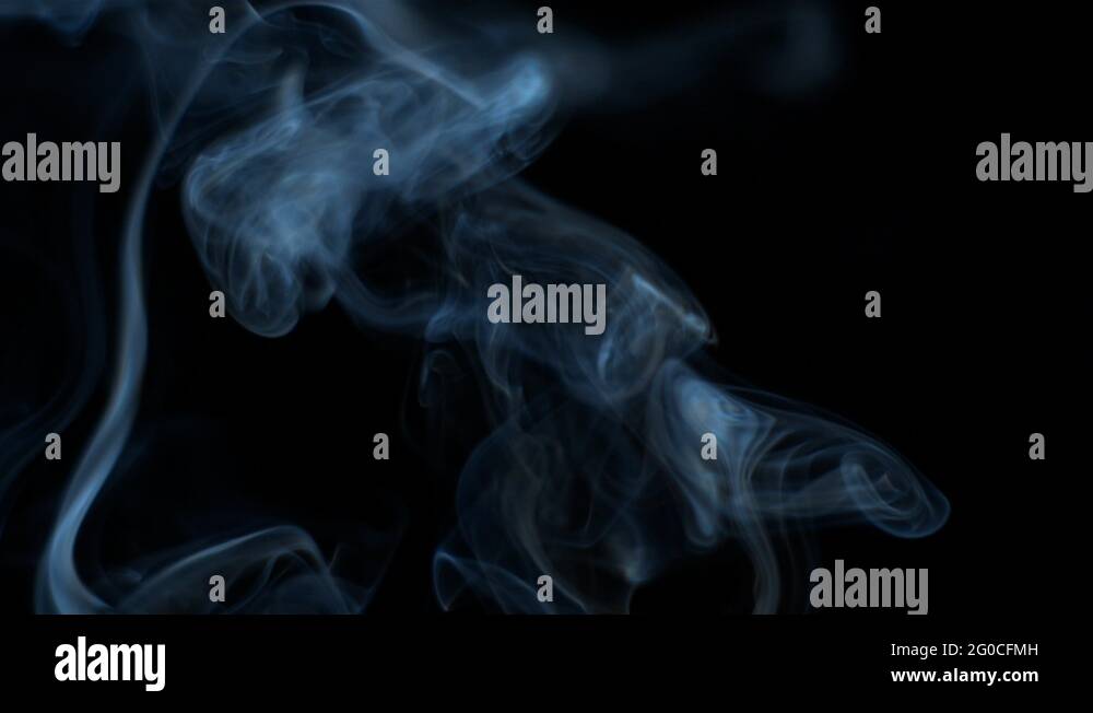 White smoke floating in the air in slow motion against black background ...