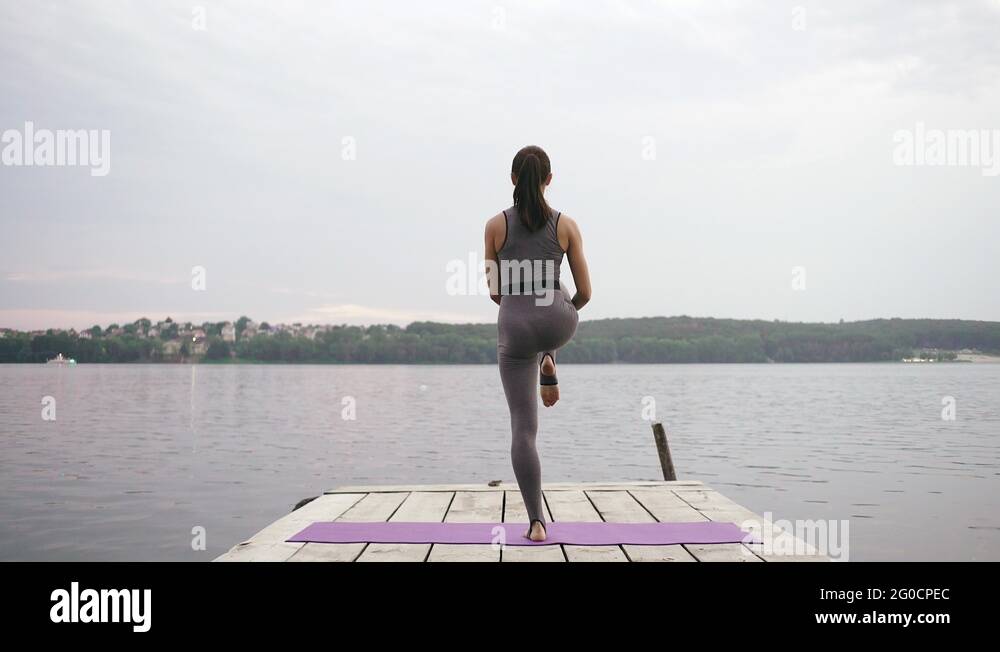 A young woman with a slender figure is engaged in gymnastics at sea ...