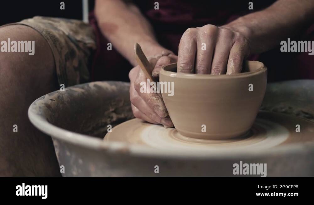 Potter shapes the clay product with pottery tools on the potter's wheel ...