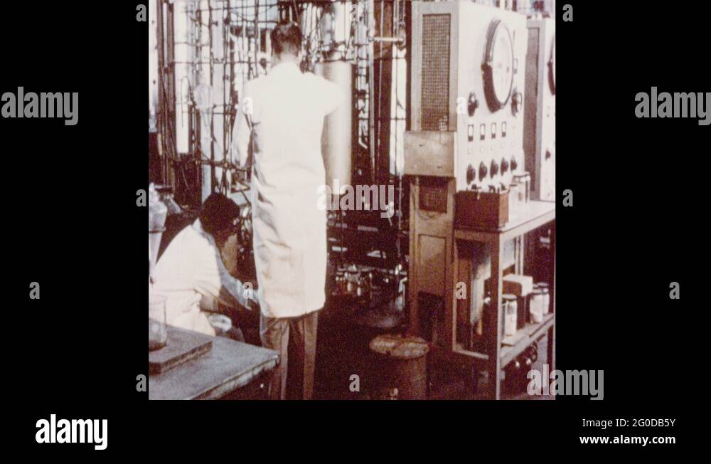 1950s: Men in white lab coats work in lab. Woman in lab coat works at ...