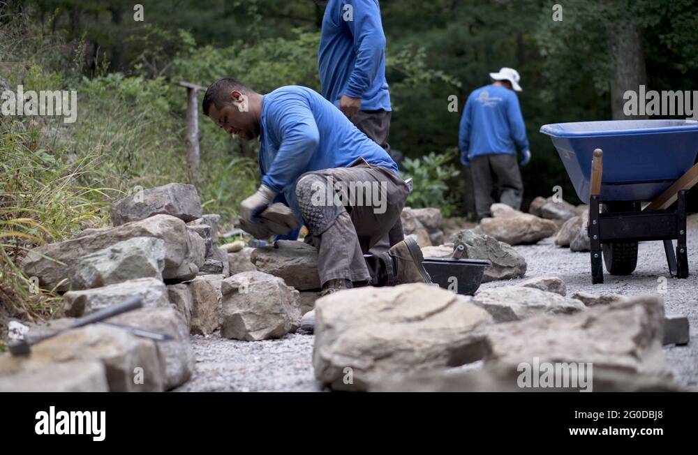 Chipping away at a large shale rock to make it fit a stone wall design ...