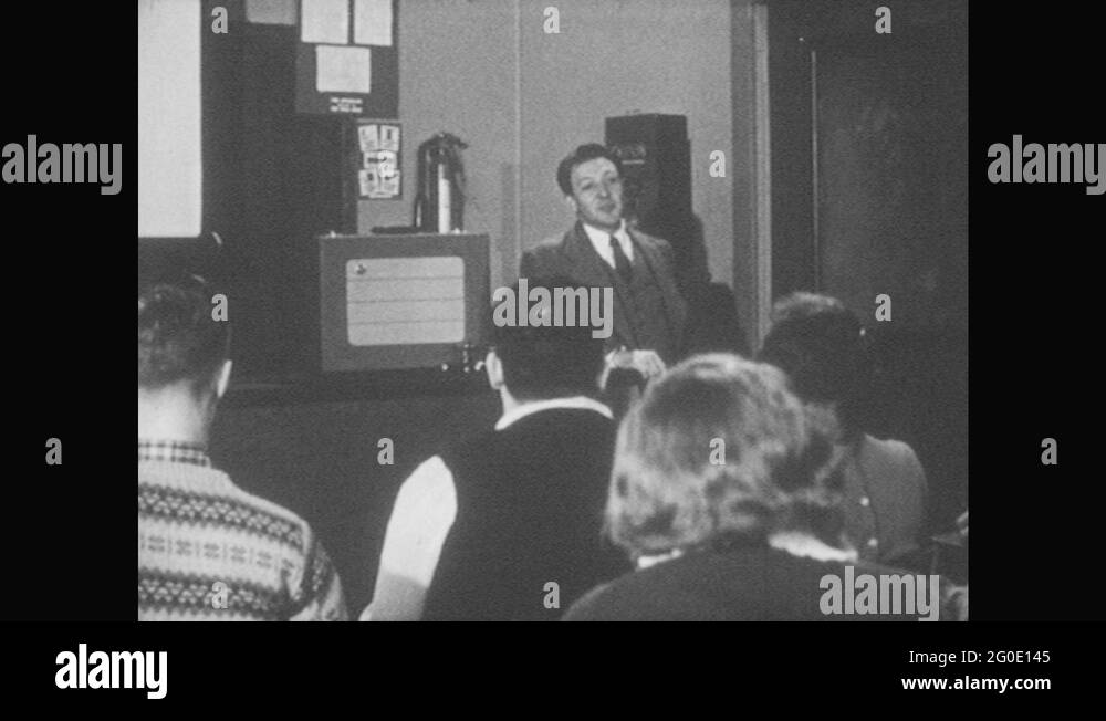 1950s: UNITED STATES: Teacher speaks with class in lesson. Man speaks ...