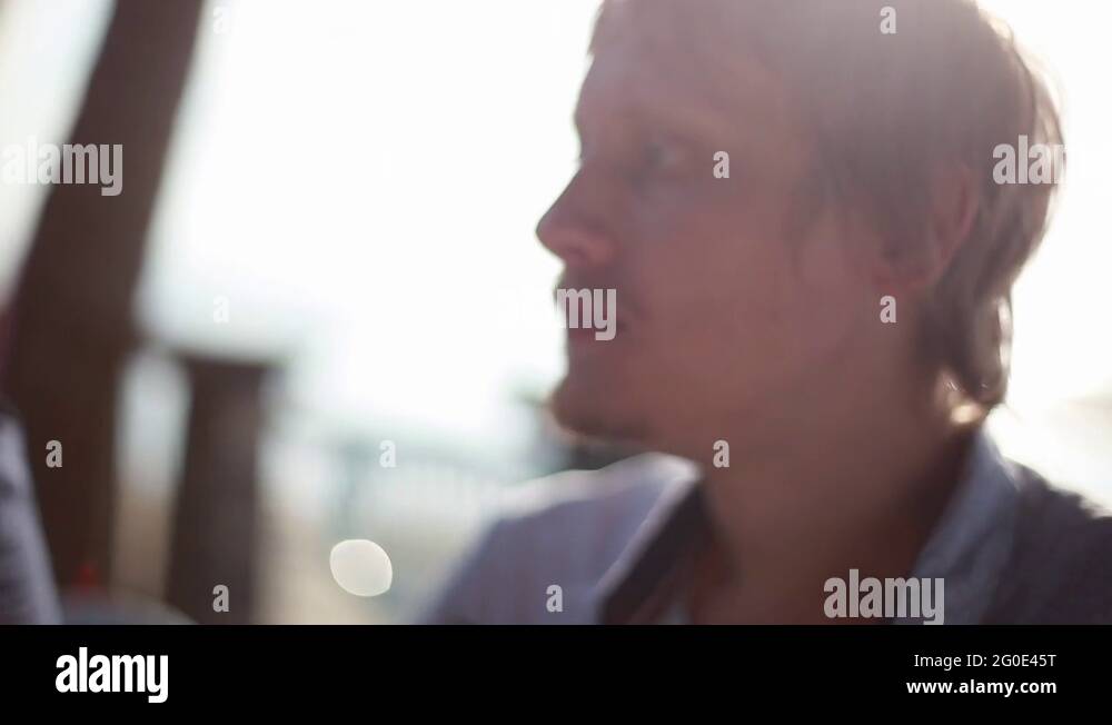 Young man eating chewing a piece of pizza in a beach cafe. 1920x1080 ...
