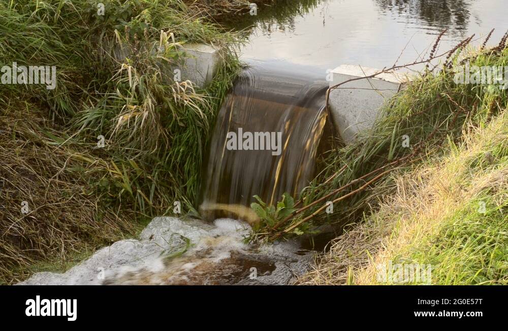 rain water flowing over a weir dam in a drainage ditch canal through ...