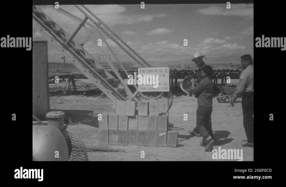 1950s: UNITED STATES: worker on drilling rig. Man and boy arrive at oil ...