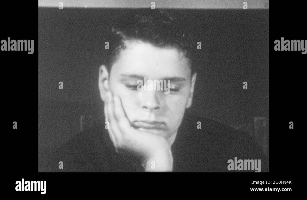 1950s: Boy with chin propped in palm of hand looks upset. He looks ...