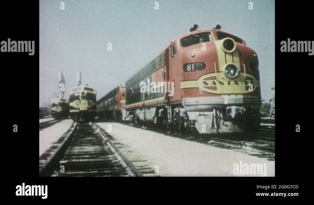 1950s: Trains and engines sit motionless on tracks. Men load linen onto ...