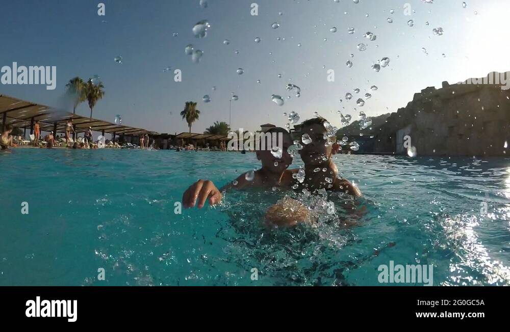 Two boys push water on a cameraman on a Turkey resort in summer in slo ...