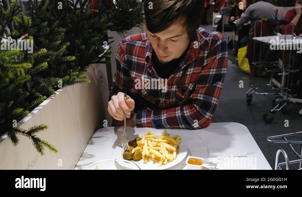 Man eating French fries at the food court of the shopping center, 4k ...