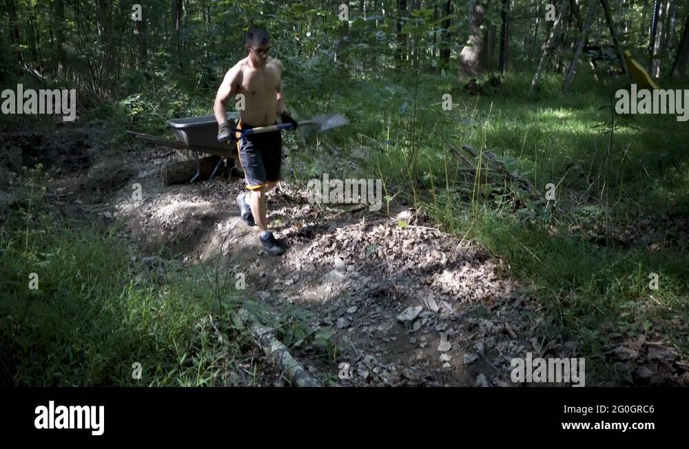 Overhead shot of young shirtless young man digging dirt and rocks and ...