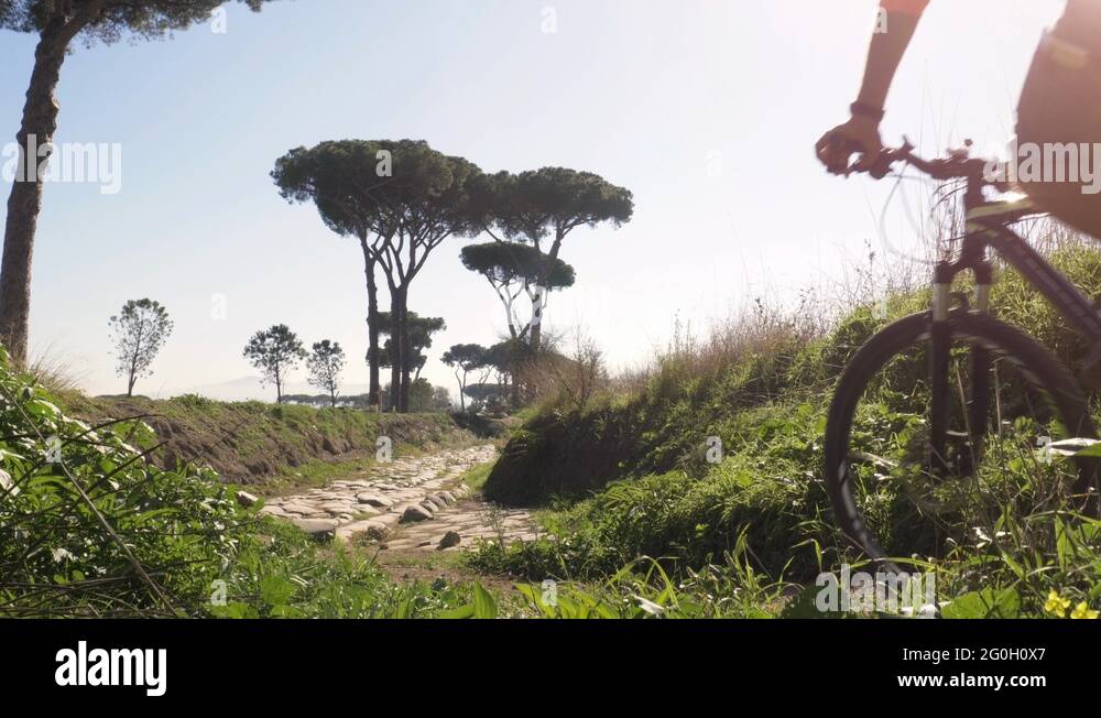 Cyclist riding bike along ancient roman cobblestone road in aqueduct ...