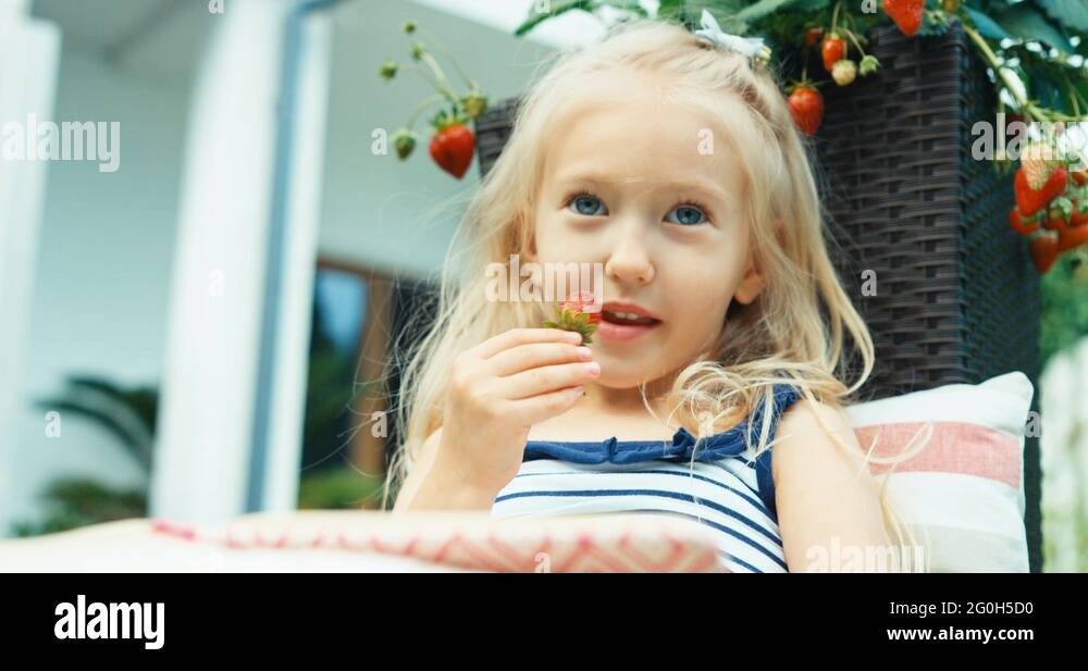 Cute little girl eating strawberry Stock Video Footage - Alamy