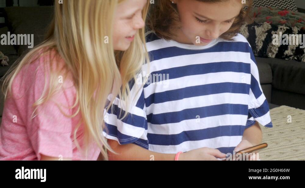 Two young tween girls scrolling through a smart phone together Stock ...