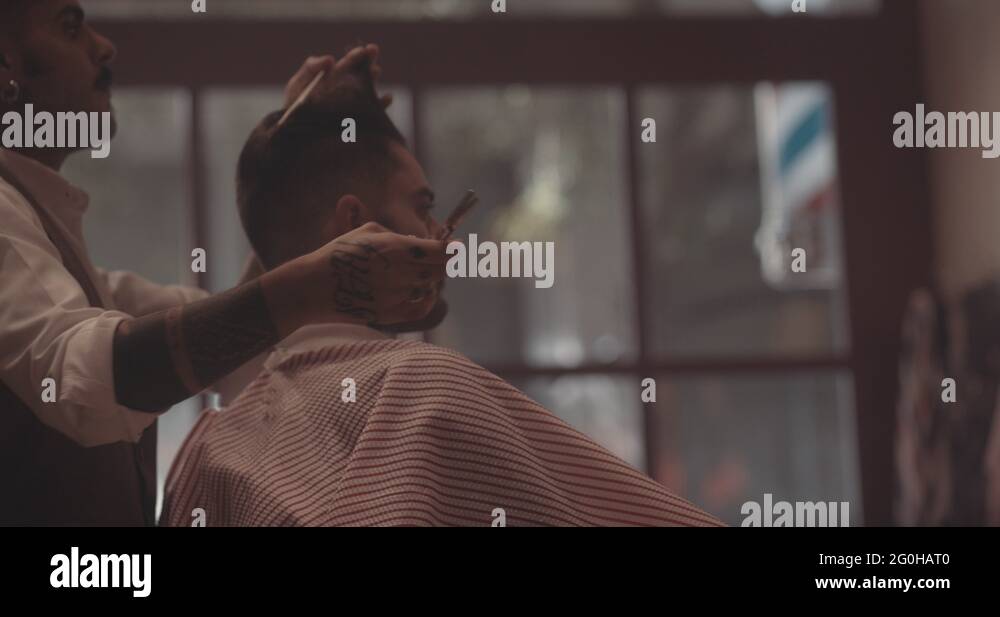 Stylish old-fashioned barber giving man haircut in vintage barber shop ...