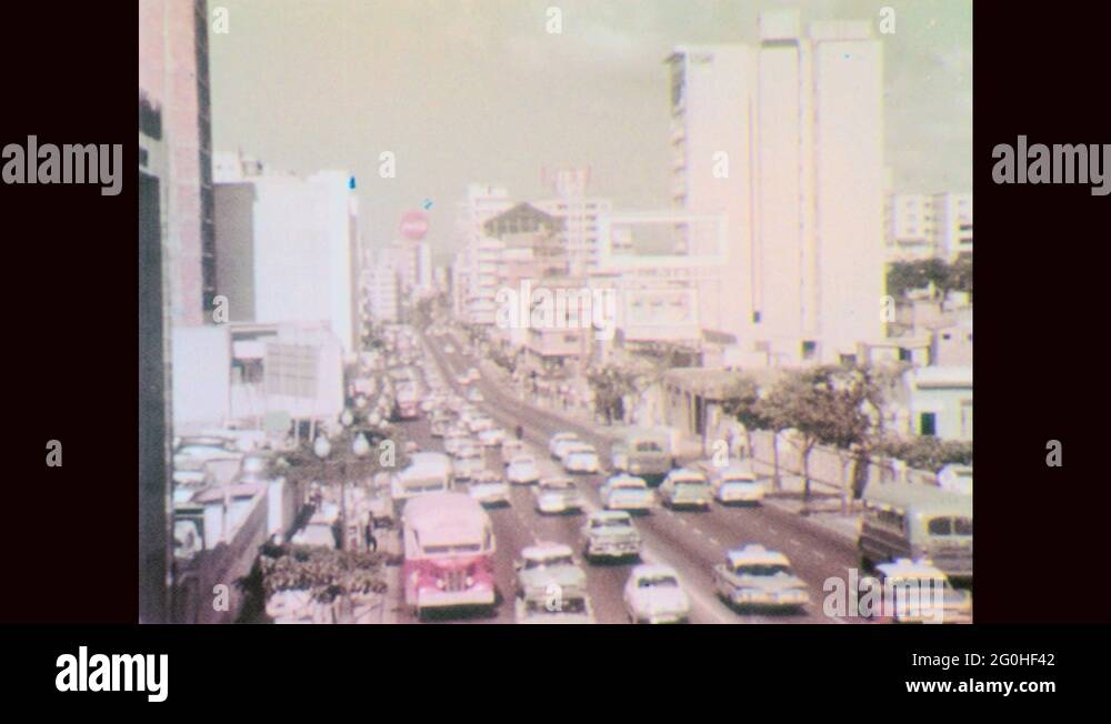 1960s: Traffic on busy city street. Cars drive along city highway. Cars ...