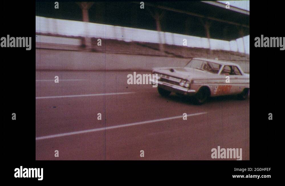 1960s: UNITED STATES: cars race at speedway track. Side profile of ...