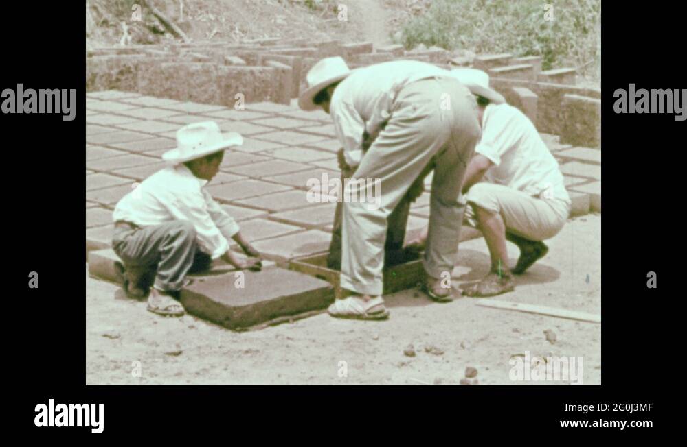 1950s: man drops mud into wood form as boy and man with mustache level ...