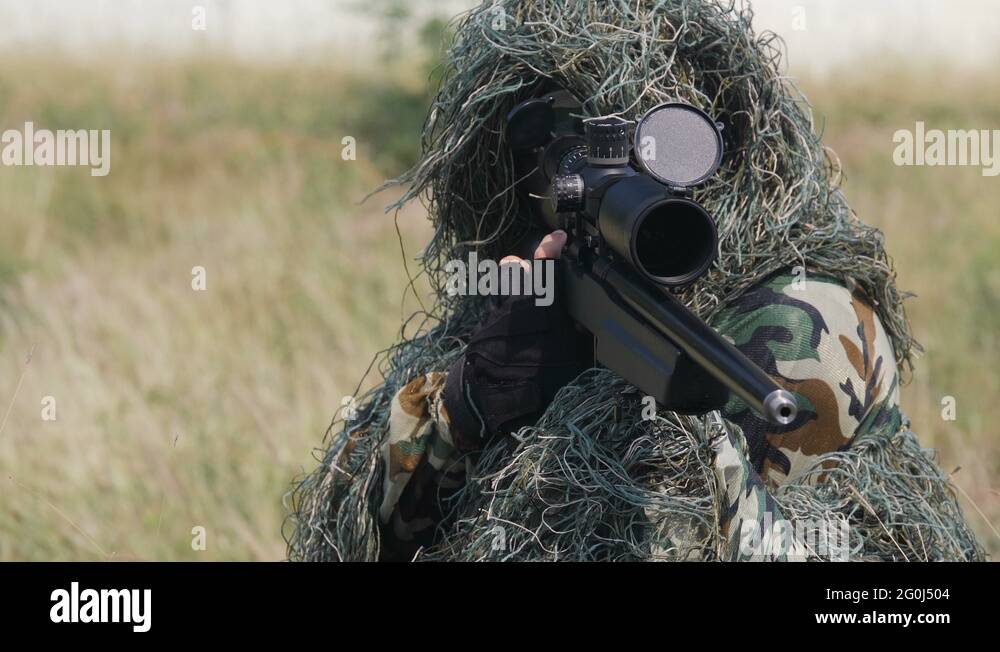 Army sniper sitting and aiming in grass carrying his gun Stock Video ...