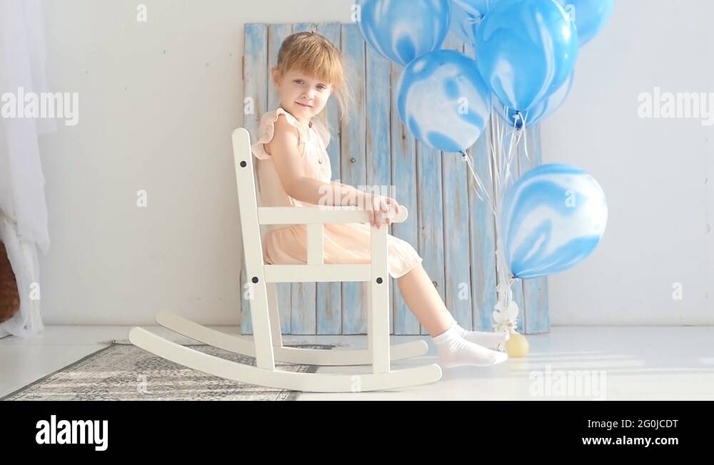 Beautiful little girl swinging in a rocking chair at the bottom of a ...