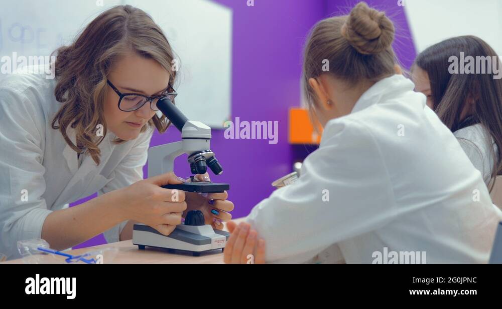 Teacher helps students set up a laboratory microscope for work Stock ...