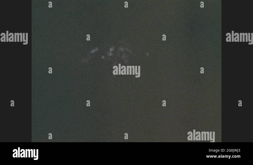 1970s: Light glows. Man operates machine. Hands hold wires that are ...