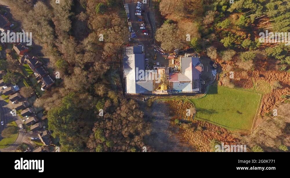 Birds eye view of mansion under construction next to suburbs and forest ...