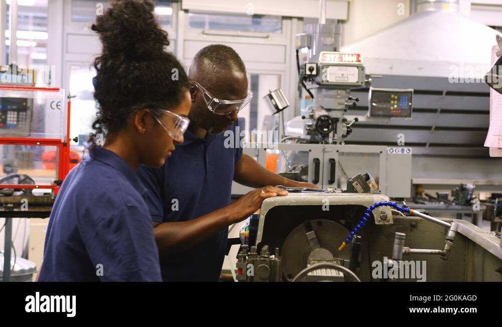 Engineer Showing Female Teenage Apprentice How To Use Lathe Stock Video ...