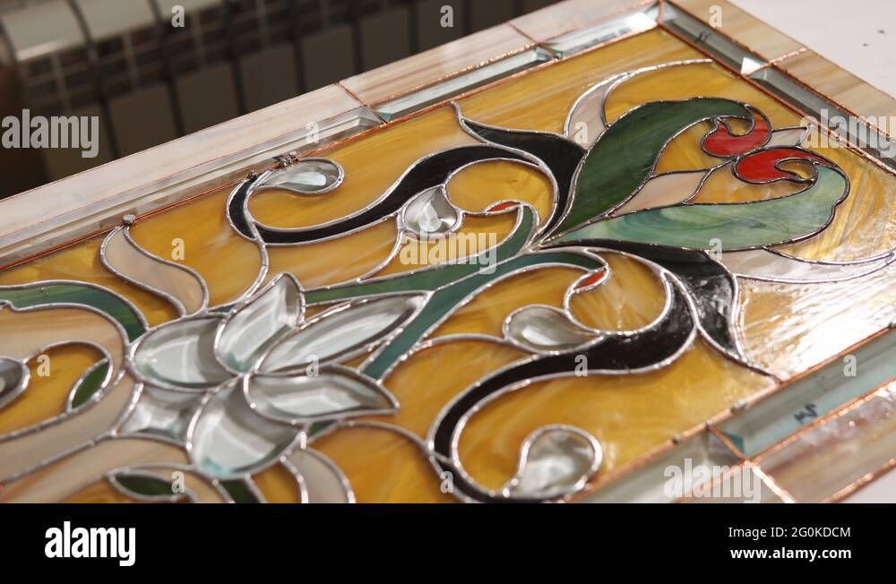 Finished stained-glass panel is lying on a work table of master in a ...