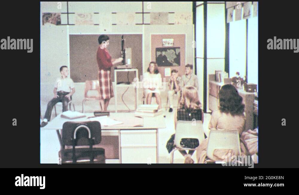 1960s: Woman next to projector in classroom, kids stand and arrange ...