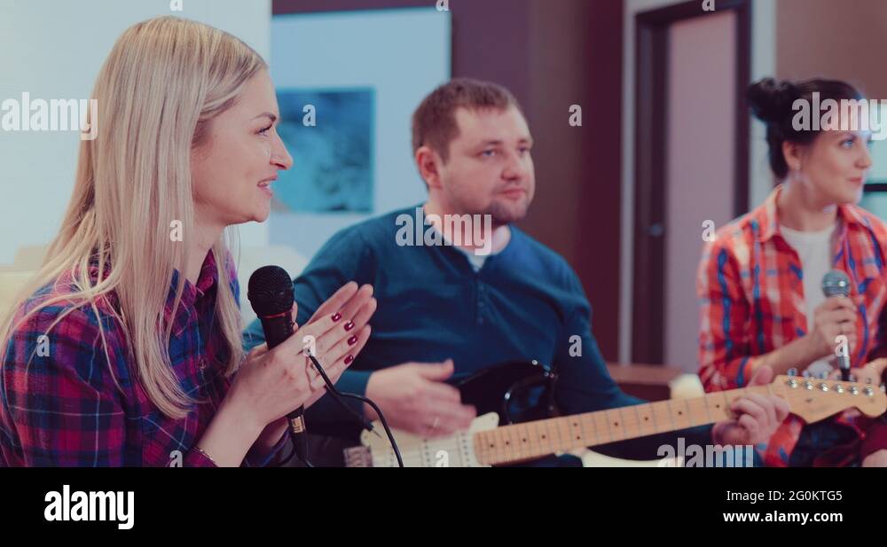 Company of merry friends sing songs into the microphone and play the ...