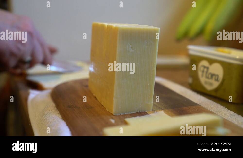 Man buttering white sliced bread to make cheese sandwich on wooden ...