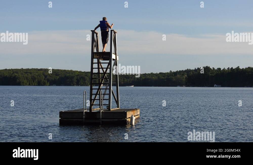 young boy jumps off floating tower into lake Stock Video Footage - Alamy