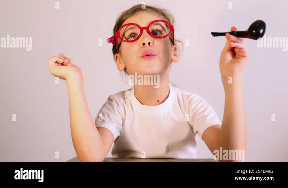 Little girl sits at table and imitates pipe smoking Stock Video Footage ...