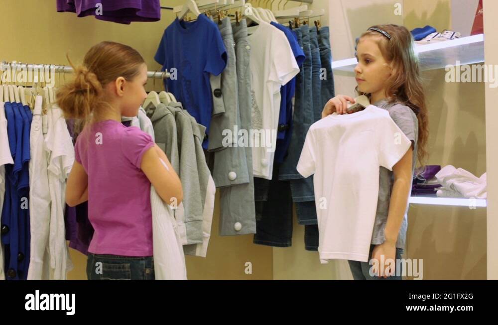 two little girls trying on same dress in store childrens clothes Stock ...