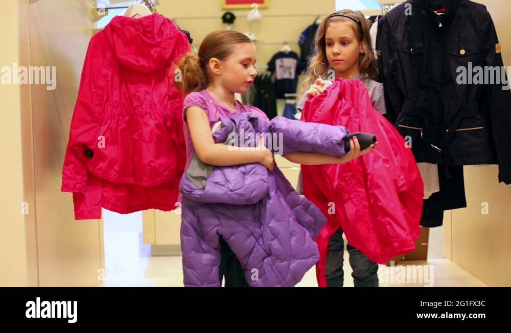 two girls wear jackets of different colors in the clothing store Stock ...