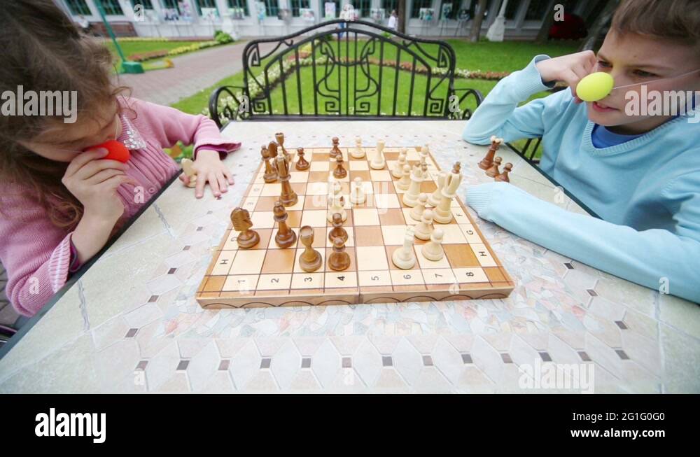 Boy and girl with clown nose playing a game of chess in park Stock ...