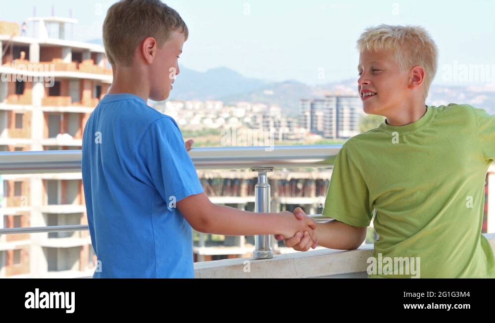 Two boys greet each other with a handshake against construction Stock ...