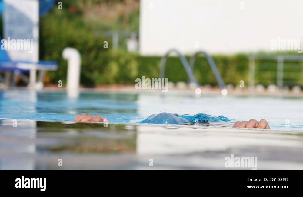 Little girl in swimming goggles goes under water turn around Stock ...