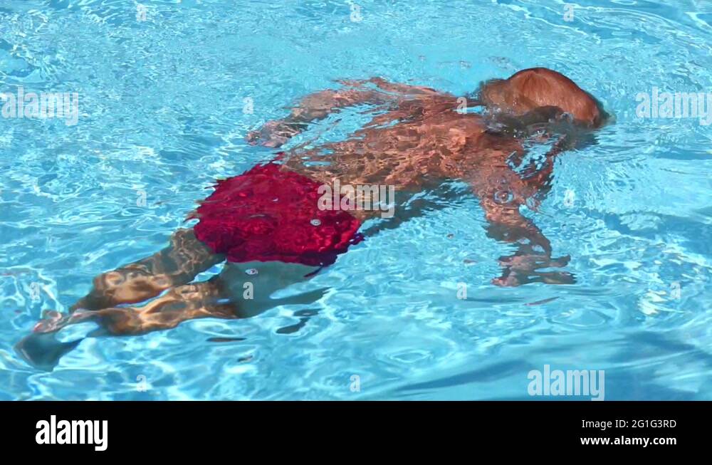 Little boy in red trunks swimming in blue pool with face down Stock ...