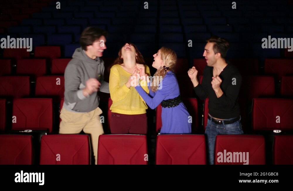 Four people in cinema watching the film then jump and rejoice Stock ...