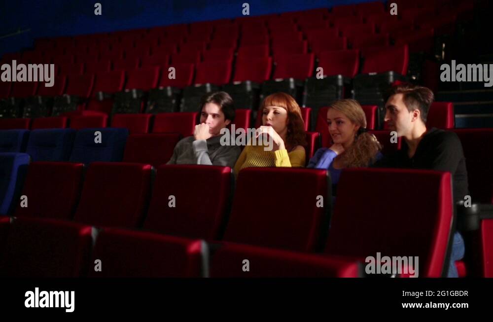 Four people sitting in the seats of dark hall cinema theater Stock ...
