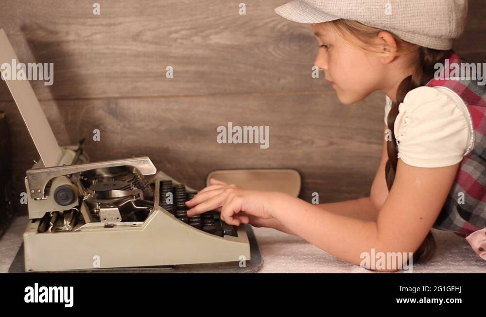 beautiful little girl typing on a typewriter, retro styling, close-up ...