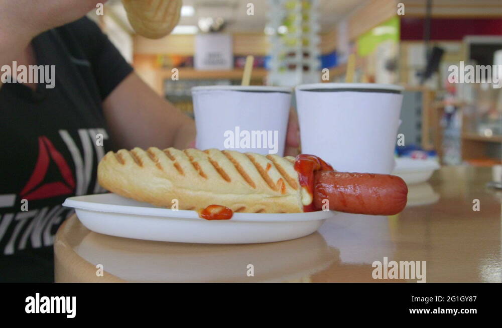 People eating hot dogs with coffee at table in convenience store Stock ...