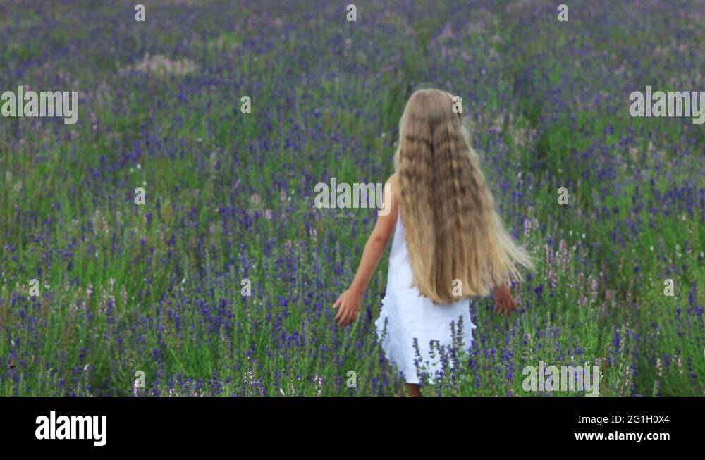 Cute girl is outgoing from camera across the field. Child is in a white ...
