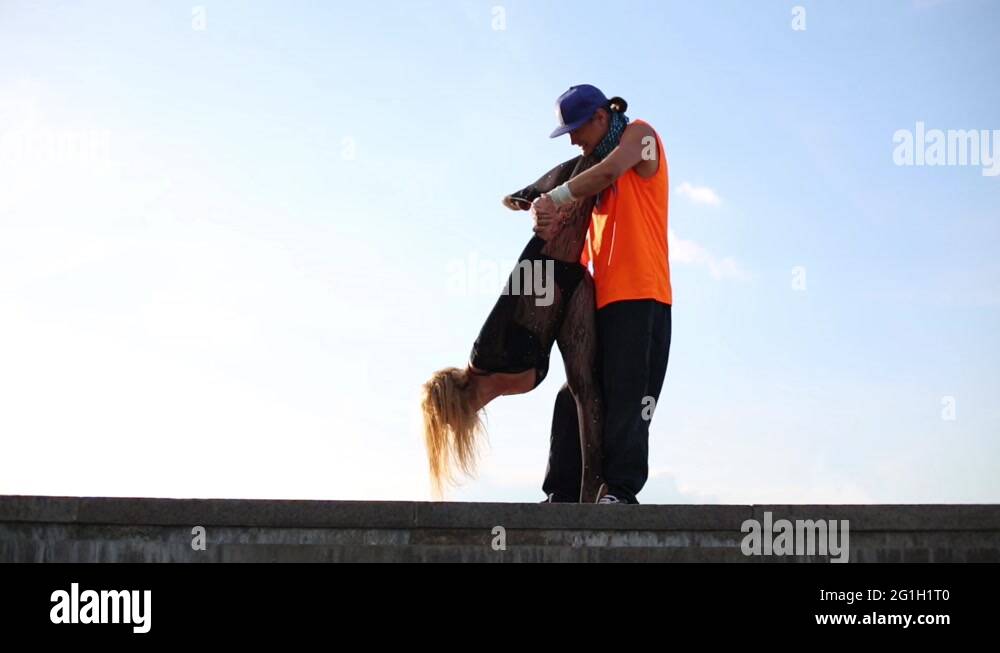 Man and pretty girl do acrobatic stunt at roof of building Stock Video ...