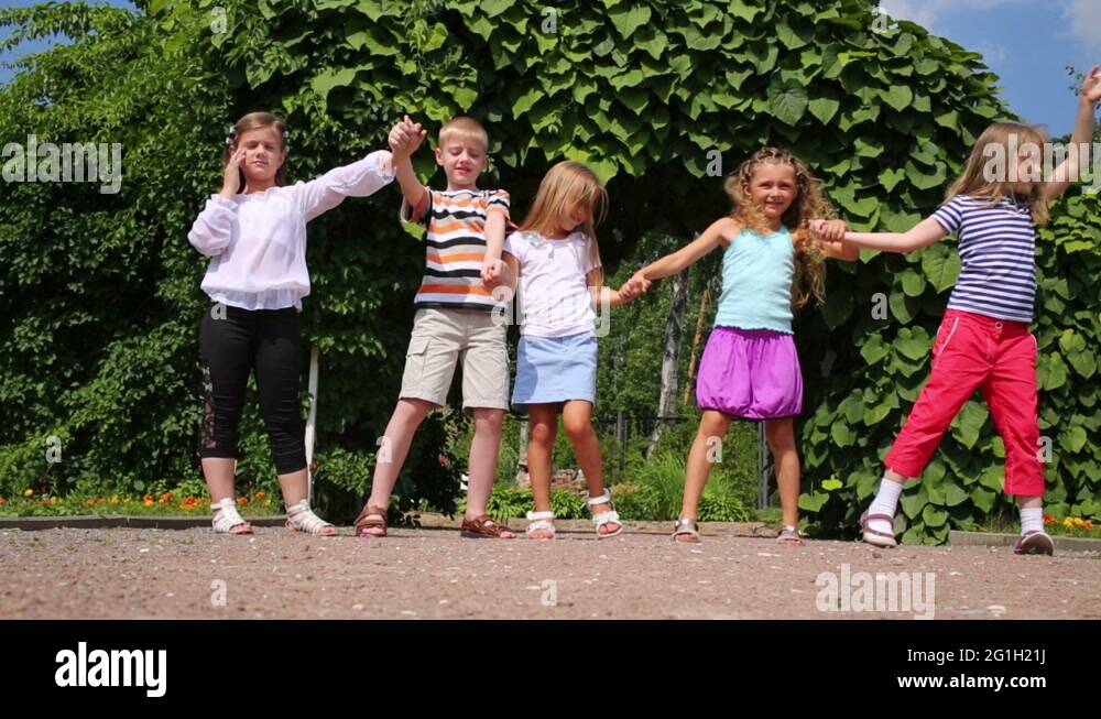 Five children hold hands and sway from side to side near arch Stock ...