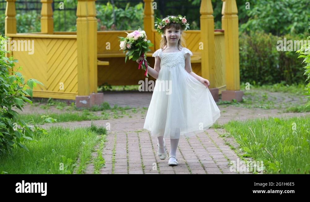 Little pretty girl in dress and wreath goes from carved arbor Stock ...