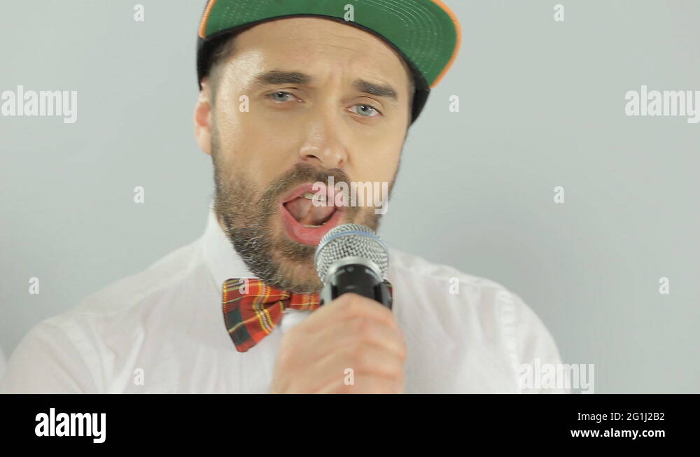 Trendy blue-eyed man with a mustache and beard sings into a microphone ...