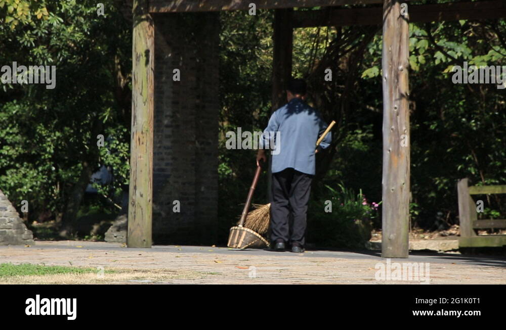 Senior man cleaning the street around old water town in Wuzhen, China ...
