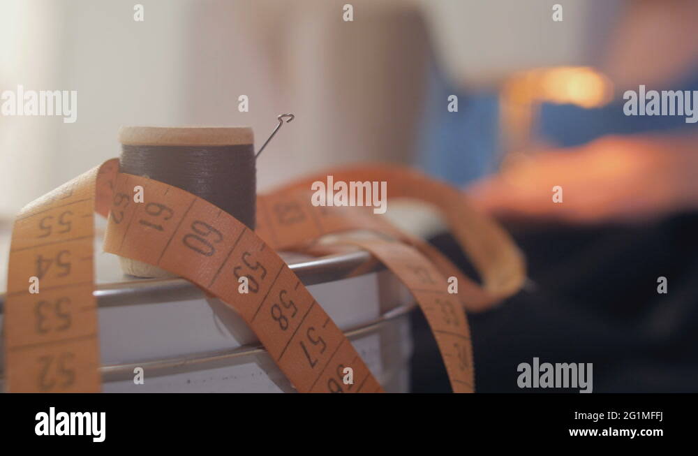 tape-measure and black thread reel, sewing machine is on background ...